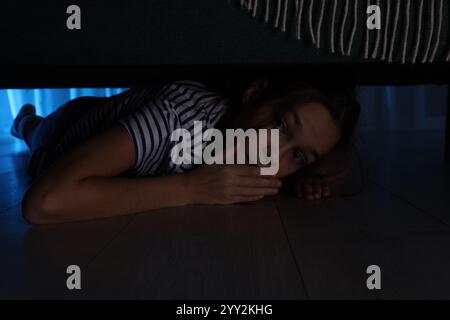 Fearful girl hiding under bed at night Stock Photo - Alamy