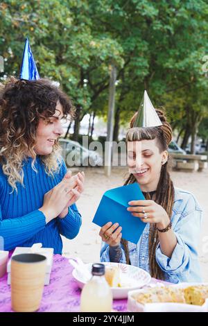 A transgender couple enjoys a birthday celebration outdoors, with one ...