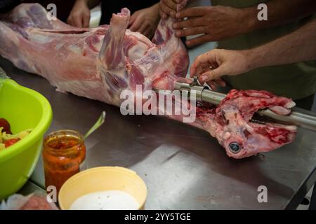 Preparing a young suckling lamb (sheep) for roasting on skewer. Whole ...