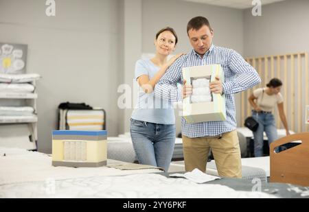 Spouses examines samples structure of spring mattress in furniture ...