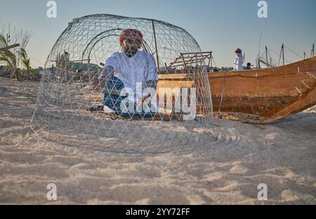 An Arabic craftsman sitting on the beach and making a fishing net in ...
