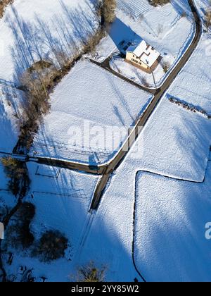 Aerial view of a snowy landscape featuring a white house nestled among ...