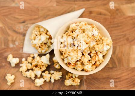 A bowl of popcorn, top-view, warm colors, light brown wooden background ...