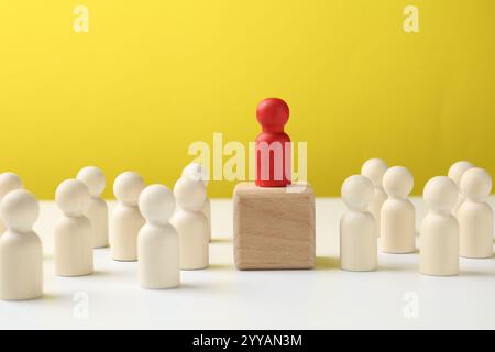 Human figures around wooden block with blue figure on top against white ...