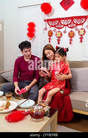 A Chinese family watches their child excitedly open a red envelope ...