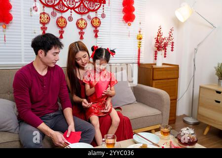 A Chinese family watches their child excitedly open a red envelope ...