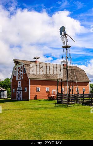 A red barn with a windmill on top and a white building with a glass ...