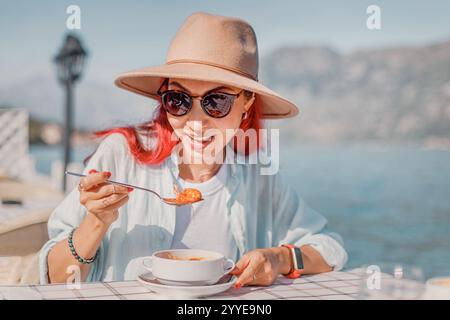 Happy tourist eating delicious seafood soup in an outdoor restaurant ...
