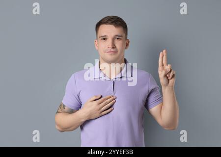 Man showing oath gesture on grey background Stock Photo - Alamy