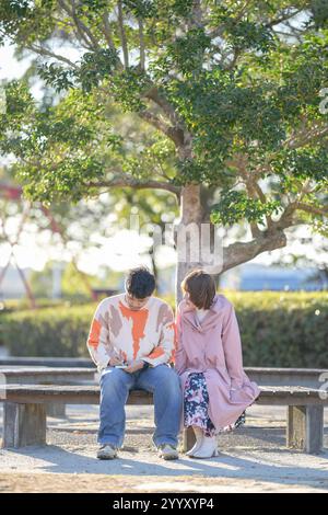 A large family is sitting on a bench in an autumn park. Happy people in ...