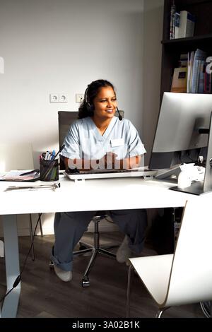 Smiling doctor wearing headset sitting at clinic Stock Photo - Alamy
