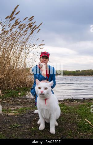 Girl walking with curious cat on her shoulder in the city park in ...