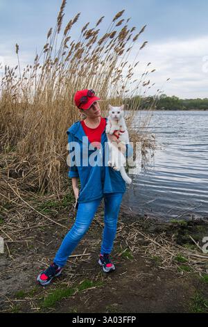 Girl walking with curious cat on her shoulder in the city park in ...
