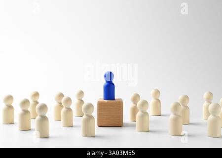 Human figures around wooden block with blue figure on top against white ...
