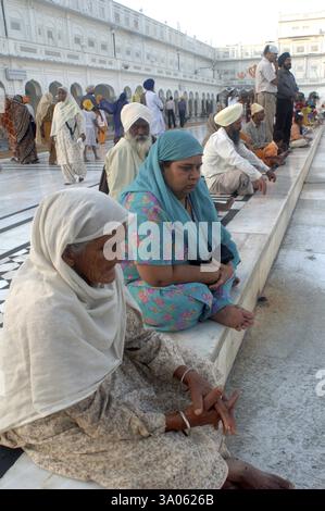 Sikh sitting on the marble steps of Amrit sarovar the lake of nectar ...