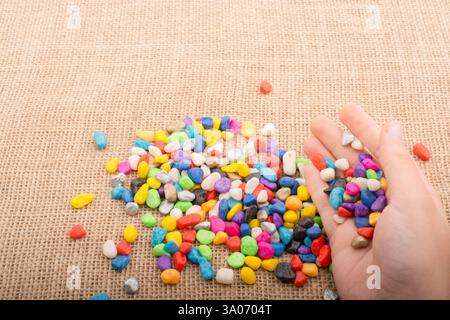 Colorful little pebbles in hand and on canvas ground Stock Photo - Alamy