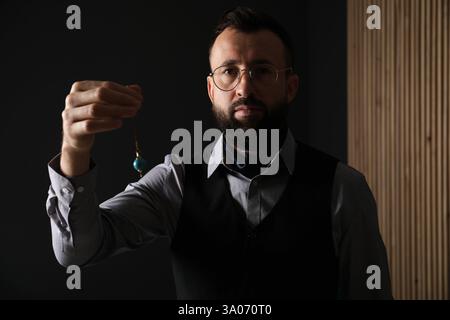Hypnosis session. Man in glasses swinging pendulum indoors Stock Photo ...