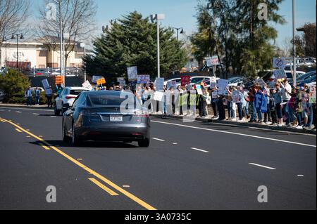 People wave signs outside of a Tesla service center location during a ...