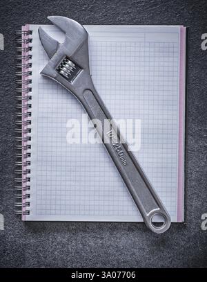 Adjustable spanner notebook on black background construction concept ...