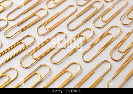 Golden paper clips on light background Stock Photo - Alamy