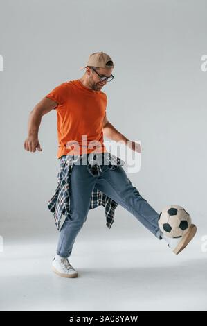 Doing tricks, playing with soccer ball. Handsome man is in the studio ...