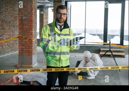 Man writing information into notepad. Detectives are collecting ...