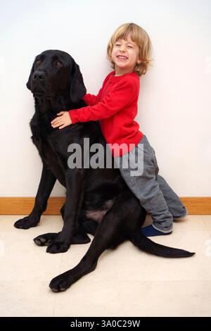 Happy toddler hugging his black labrador retriever dog Stock Photo - Alamy