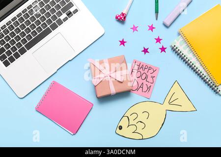 Laptop, gift box, notebooks and sticky notes on blue background. April ...