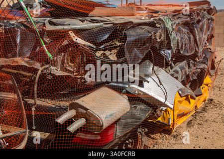 Compact cars smashed by the crusher at a salvage yard and stacked ready ...