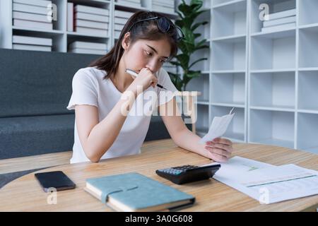 Young woman analyzing receipt and financial documents at home office ...