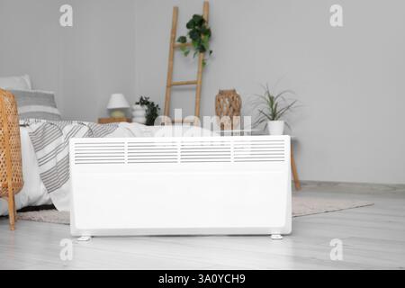 Electric heater on floor near bed in bedroom Stock Photo - Alamy