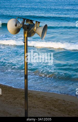 Conical loudspeakers on a pole against the backdrop of ocean waves ...