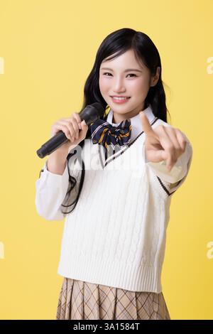 A girl wearing a school uniform and singing with a microphone Stock ...