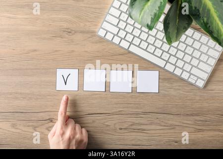 Woman pointing at checkbox with tick mark at wooden table, top view ...