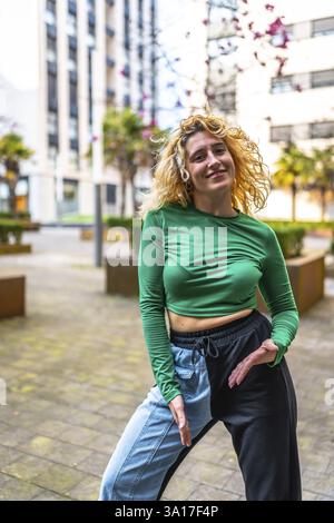 A cheerful blonde woman enjoys music while showcasing her stylish denim ...