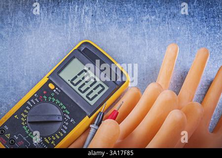 Digital multimeter insulating rubber gloves on metallic background ...