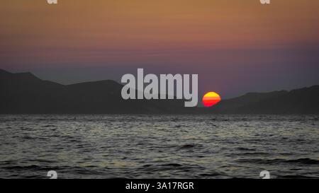 Beach sunset setting behind Kalymnos island from Kos island, Greece ...