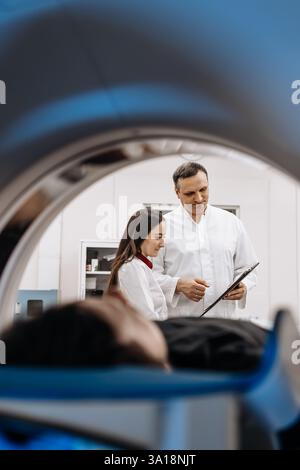 The patient lies inside an MRI or CT machine where the scan is ...