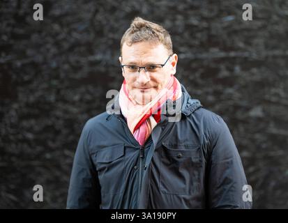 Portrait of a 46 yo man with glasses against a green background in ...