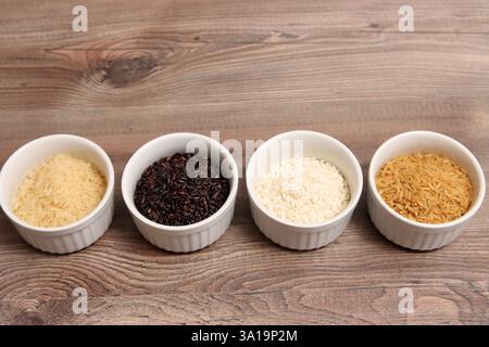 Bowls with different types of raw rice on wooden background Stock Photo ...