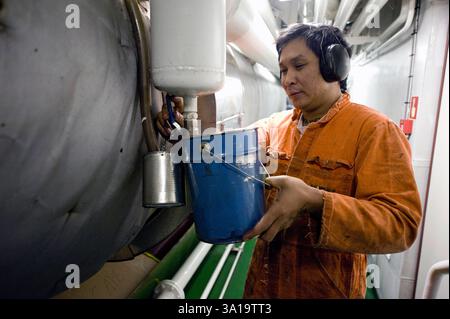 Marine engineer working in ship's workshop in engine control room ECR ...
