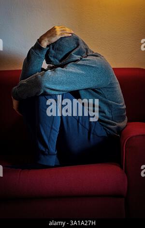 Sad man curled up in bed with hands over his face Stock Photo - Alamy