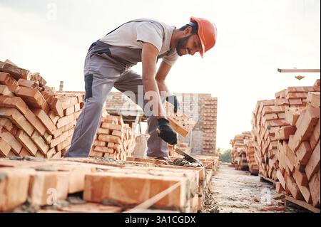 Side view, working and placing the bricks. Handsome Indian man is on ...