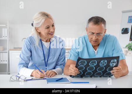 Doctors studying MRI scan at table in clinic, back view Stock Photo - Alamy