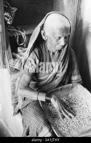 Old woman cleaning grain, Lokur village, Dharwar district, Karnataka ...