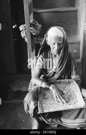 Old woman cleaning grain, Lokur village, Dharwar district, Karnataka ...
