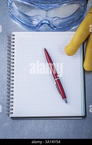 Plastic goggles protective gloves copybook pen on metallic background ...