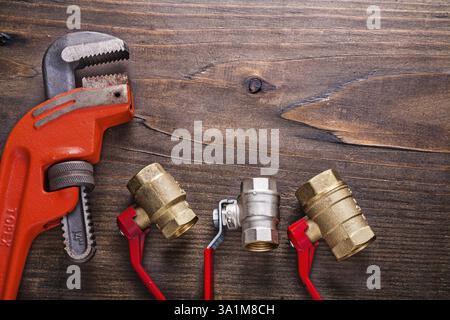 plumbers fixtures with red handles and monkey wrench on vintage wooden ...