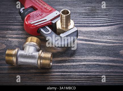 Metal pipe wrench brass equal tee hose nipple on wooden board Stock ...
