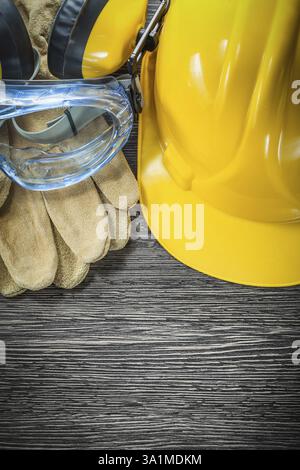 Safety gloves goggles earmuffs hard hat on wooden board Stock Photo - Alamy